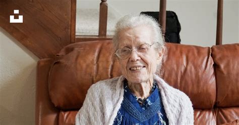 파란색 셔츠와 회색 가디건을 입은 여자가 갈색 소파에 앉아 있다 사진 Unsplash의 무료 초상 이미지