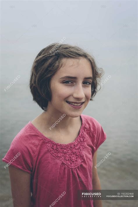Portrait Of Smiling Pre Adolescent Girl In Front Of Lake Water