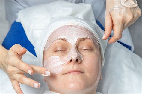 미용사 의사가 미용 클리닉에서 중년 여성 고객을 위한 안티 에이지 시술 얼굴 및 머리 마사지를 하는 클로즈업 미용사 손 미용사 스킨케어 트리트먼트 건강 관리 치료 건강관리와