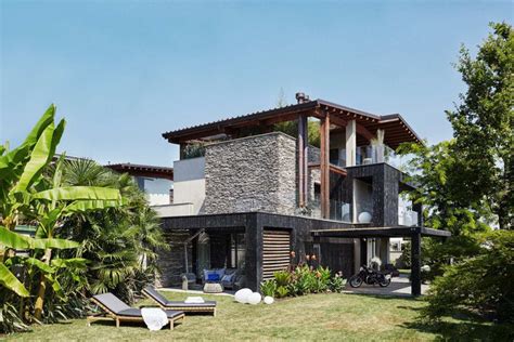 Современный загородный дом с многослойным фасадом из камня и дерева