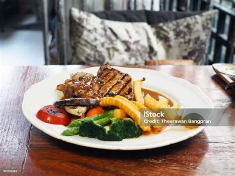 소스와 함께 맛 있는 돼지고기 브로콜리와 아스파라거스 체리 토마토 가지 등 구운된 야채를 곁들인 고 튀긴 감자 접시 나무