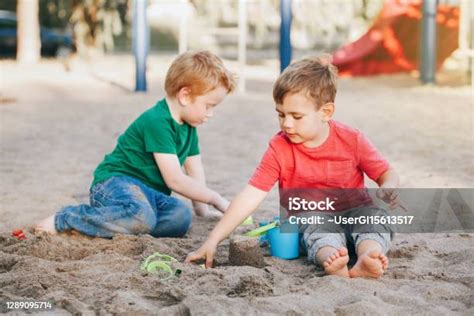 해변 장난감을 가지고 노는 샌드 박스에 앉아있는 두 명의 백인 아이들 놀이터에서 함께 즐거운 시간을 보내는 어린 소년 친구들 아이들을위한 여름 야외 활동 여가 시간 라이프