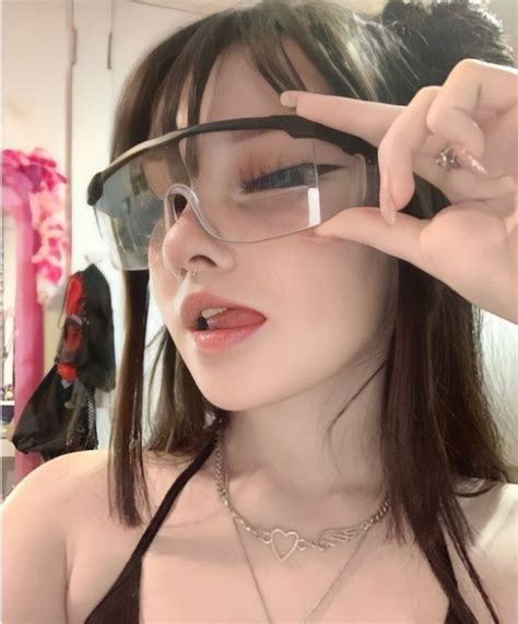 A Woman Wearing Glasses And Holding Her Hand Up To The Side With One