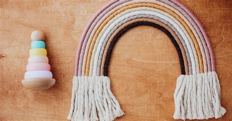 나무 테이블에 아이를 위한 세련 된 나무 장난감입니다 반지와 마크라메 무지개가 있는 현대적인 다채로운 나무 피라미드 유아를