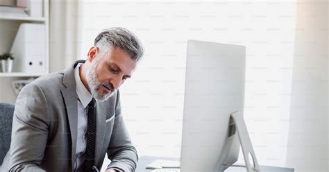 데스크톱 컴퓨터를 가진 사업가가 사무실의 테이블에 앉아 메모를 하고 있다 사진 Unsplash의 책상 이미지