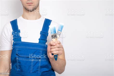 파란색 바지를 입은 한 젊은 남자가 손에 건설 브러시를 들고 있다 흰색 배경입니다 텍스트에 대한 장소입니다 개선에 대한 스톡 사진 및 기타 이미지 Istock