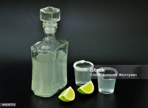 잘 익은 석회 조각 옆에 가장자리에 소금이 든 데킬라 두 샷과 검은 배경에 알코올 한 병 0명에 대한 스톡 사진 및 기타 이미지