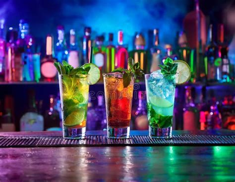 Three Mojitos Cocktails At The Bar With Bottles Behind Stock