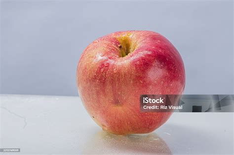 밝은 배경에 놓인 피부에 물방울이 있는 신선한 빨간 사과의 클로즈업으로 건강한 열대 과일의 과즙 질감 수분 공급 및 자연스러운 신선도를 보여줍니다 겉껍질에 대한 스톡 사진