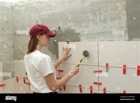 Woman Tiling Bathroom Walls Pressing Tile Into A Glue With Rubber