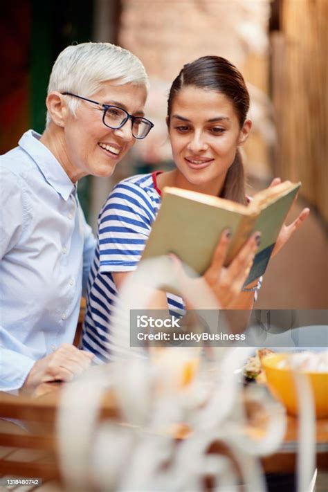 다른 세대의 두 여성 친구가 바에서 음료를 마시며 함께 책을 읽습니다 레저 바 우정 야외 가족에 대한 스톡 사진 및 기타 이미지 Istock