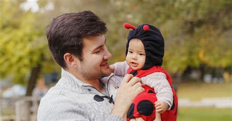 무당벌레 의상을 입은 귀여운 사랑스러운 아기 소녀와 함께 행복한 미소를 짓고 있는 백인 아버지 아빠 가을 가을 공원 야외에 있는 가족 할로윈 계절 휴가 개념입니다