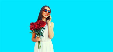 파란색 배경에 하트 모양의 선글라스에 빨간 장미 꽃다발을 들고 스마트폰으로 전화하는 아름다운 웃는 여자의 초상화 25 29세에 대한 스톡 사진 및 기타 이미지 Istock