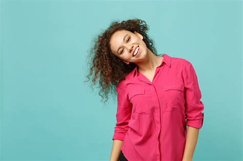 스튜디오에서 파란색 청록색 벽 배경에 고립 된 머리를 끼고 있는 캐주얼 복장에서 웃는 아프리카 소녀의 초상화 사람들은 진심으로 감정 라이프 스타일 개념입니다 복사 공간을