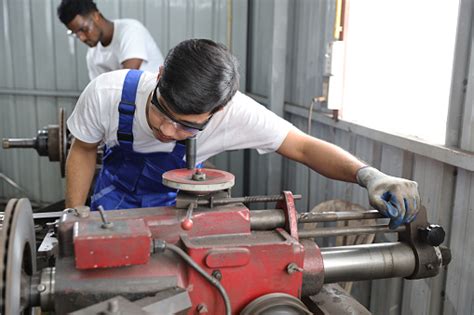 금속 선반 기계를 사용하여 보호 유니폼을 입은 다민족 기술자 또는 노동자는 차고에서 자동차 디스크 브레이크 연마를 작동합니다 유지 보수 자동차 및 검사 차량 부품 개념