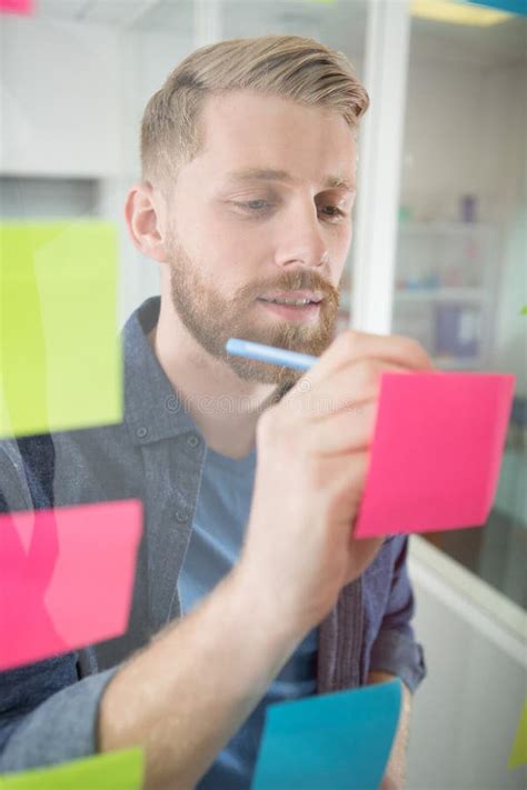 Man Writing At Sticky Notes On Window Stock Photo Image Of Male Spectacle 261156792