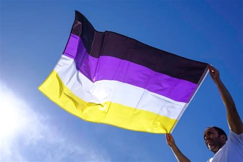 Premium Photo Caucasian Adult In White T Shirt Holds Non Binary Flag