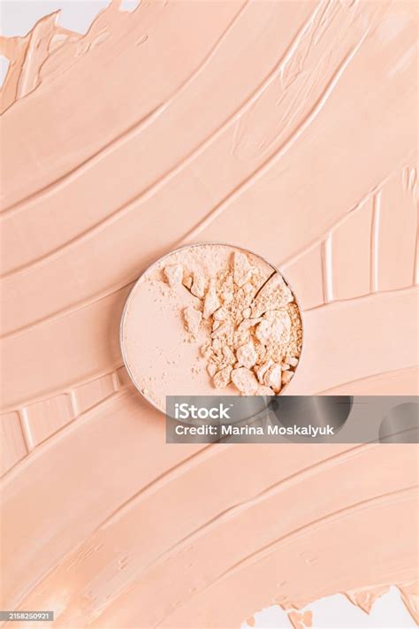 리퀴드 파운데이션 파우더를 배경으로 자연스러운 톤의 부서진 조각이 있는 컴팩트한 파우더의 둥근 블록이 서 있습니다 화장품