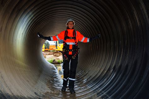 여성 엔지니어가 대형 강관 내부에서 일하고 있습니다 작업자들은 산업 플랜트에서 석유 천연 가스 및 연료를 운송하기 위한 파이프라인을 건설합니다 강철에 대한 스톡 사진 및