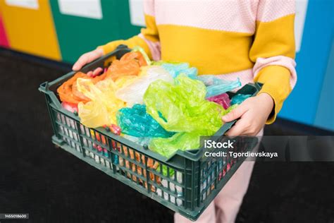 다른 비닐 봉지로 상자를 들고 있는 소녀의 클로즈업 아이들이 재활용 쓰레기통에 비닐 봉지 쓰레기를 던지고 있다 폐기물 제로 재활용 환경 문제 아이에 대한 스톡 사진 및 기타