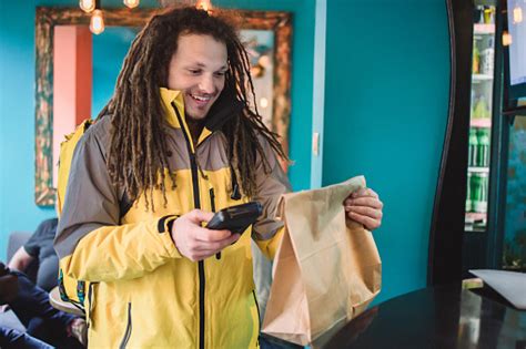 레스토랑에서 소포를 집어 들고 공포에 질린 젊은 배달 남자 20 24세에 대한 스톡 사진 및 기타 이미지 20 24세 Brand Name Smart Phone