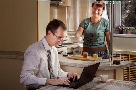 젊은 남자는 바쁜 요리 여자의 배경에 집에서 컴퓨터에서 작동합니다 가정 주방에 대한 스톡 사진 및 기타 이미지 가정 주방