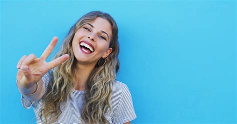 여성 초상화 파란색 배경 모형 공간 및 스튜디오에서 승리에 평화를 위한 미소 얼굴 행복한 Z 세대 모델 및 투표 승리 아이콘 및 자유의 지지를 위한 손 이모티콘이 있는 V