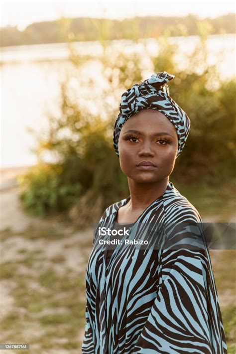 히잡 미소를 지으며 자신감 넘치는 무슬림 흑인 소녀 녹색 배경에 국가 다채로운 드레스를 입고 아프리카 여성 히잡이라는 이름의 스카프를 입고 검은 소녀의 라이프 스타일 흑인을