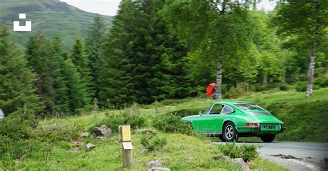 나무와 산을 배경으로 언덕에 주차된 차 사진 Unsplash의 무료 자동차 이미지