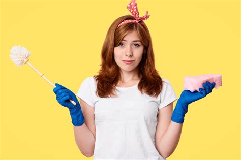 불쾌 하 게 여자의 스튜디오 샷 청소 도구를 보유 하 고 집안일을 미 워 캐주얼 옷과 장갑 화장실을 청소 하려고 착용 브러시와 스펀지 노란색에 고립 된 슬픈 아름 다운 여자