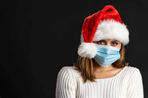 크리스마스를 위한 산타 모자와 N95 보호 얼굴 마스크를 착용하고 카메라를 바라보는 아름다운 젊은 성인 여성 20 24세에 대한 스톡 사진 및 기타 이미지 Istock