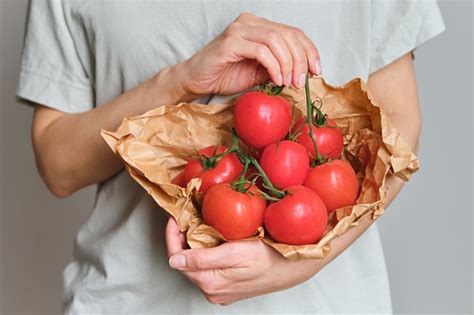 소녀는 그녀의 손에 토마토를 들고있다 종이 포장에 신선한 빨간 토마토를 익은 건강 식품 유기농 야채 천연 비타민 먹기위한 원료 엄선된 바이오 토마토 가정 주방에 대한 스톡