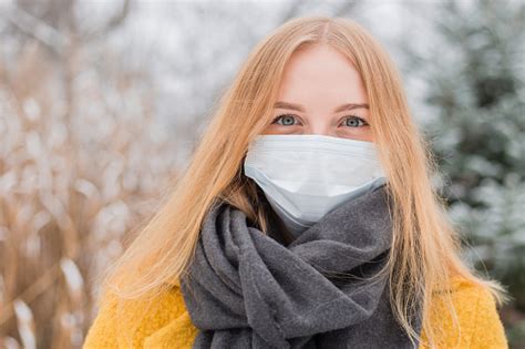 자연 배경위에 흰색 의료 용 얼굴 마스크를 착용 하는 젊은 금발 여자 올해의 트렌디 한 색상 2021 조명 노란색과 궁극적 인