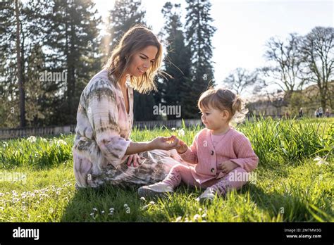 Mother Gives Her Little Daughter A Flower On A Meadow Hi Res Stock
