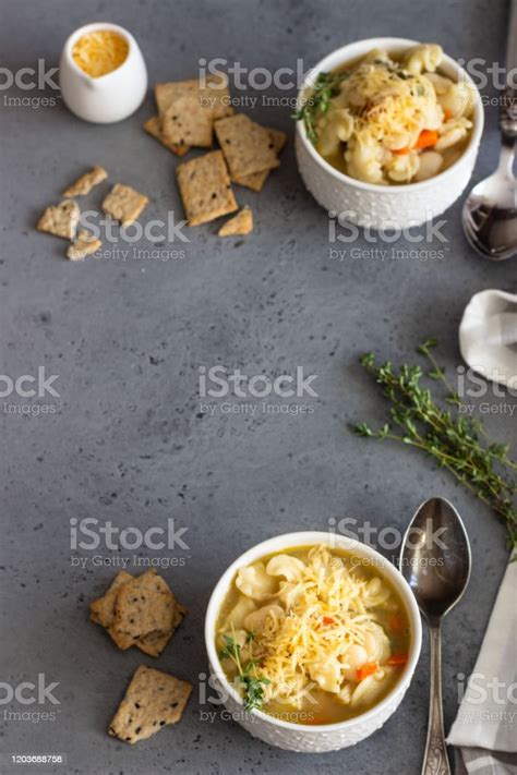 파스타와 흰 콩을 얹은 이탈리아 수프 미네스트론의 흰 그릇에 신선한 백리향을 얹고 회색 콘크리트 배경에 크래커와 함께 나옵니다 채식 음식 개념입니다 0명에 대한 스톡 사진