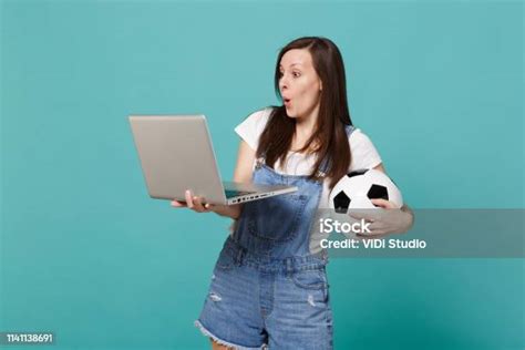 놀란 젊은 여자 축구 팬 축구 공을 들고 파란색 청록색 벽 배경에 고립 된 노트북 Pc 컴퓨터를 사용 하 여 사람들의 감정 스포츠 가족 레저 라이프 스타일 개념입니다 복사