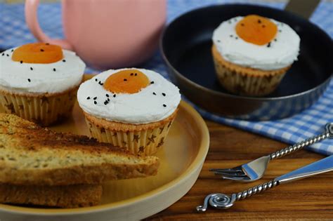 홈메이드 프라이드 에그 바닐라 컵케이크 의 이미지 종이 케이크 케이스에 흰색 파이프 착빙 프로스팅과 말린 살구를 얹고 구운 통밀 빵 삼각형 조각 배경에 분홍색 우유 주전자