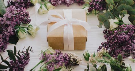 흰색 나무 배경에 라일락과 장미 꽃이 있는 세련된 선물 상자 해피 어머니의 날과 여성의 날 개념 분홍색 리본과 꽃 구성으로