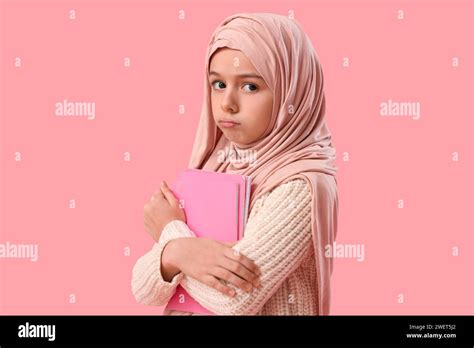 Sad Muslim Girl In Hijab Holding Copybooks On Pink Background Stock