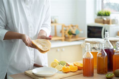 여자의 손과 콤부차 차와 함께 차 버섯을 들고 있는 코비 차 버섯 콤부차를 만들기 위한 발효 과정을 시작하는 스코비 차 버섯 소화 시스템의 균형을 잘 잡는 프로바이오틱 영양