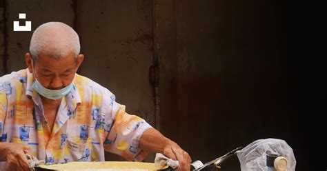 파란색과 흰색 격자 무늬 드레스 셔츠를 입은 남자가 음식을 썰는 칼을 들고 있다 사진 Unsplash의 무료 페탈링 거리 시장 이미지