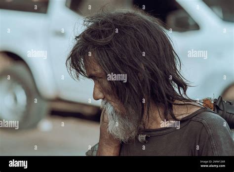 A Shallow Focus Of A Male Beggar With Long Unkempt Hair And A Beard In