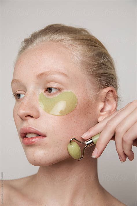 Model With Green Jade Roller And Under Eye Patch By Stocksy