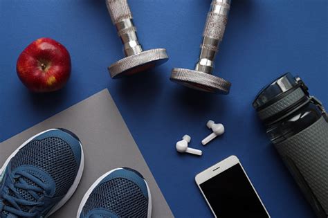 스포츠 장비 카피 공간이있는 파란색 배경에 운동화 아령 물 사과 스마트 폰 및 이어폰이있는 병 건강한 라이프 스타일 다이어트 스포츠 및 체중 감량 개념 0명에 대한 스톡