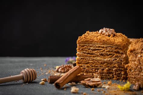 회색 콘크리트 배경에 호두와 계피가 있는 전통적인 꿀 케이크 꿀 베이스와 화이트 사워 크림 충전물을 곁들인 레이어드 케이크의 사각형 조각 호두에 대한 스톡 사진 및 기타