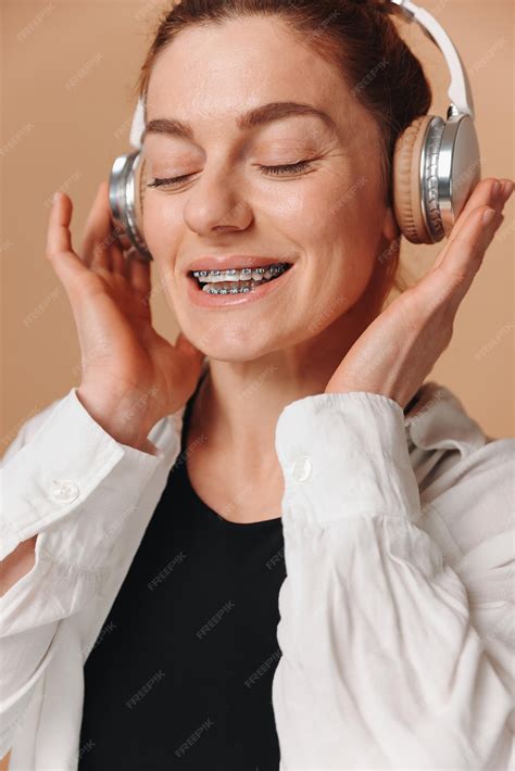 Premium Photo Woman Smiling With Braces On Her Teeth And Listening To Music In Headphones On A