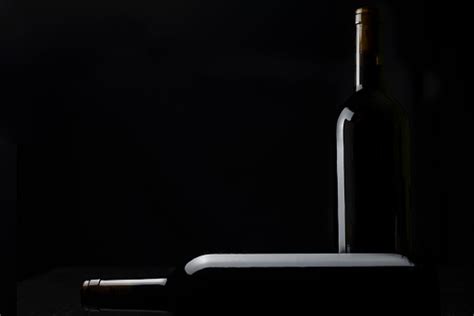 레드 와인 두 병 하나는 바닥에 누워 있고 다른 하나는 빛이 거의없는 옆구리에 서서 검은 색 배경에 유리의 구호 만 드러냅니다 공간을 복사합니다 코르크 스크류에 대한 스톡