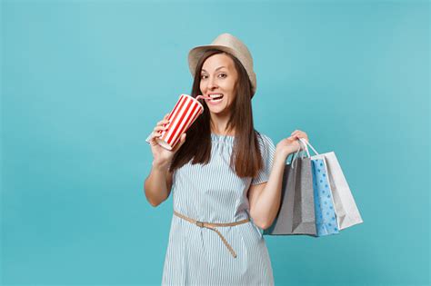 초상화 꽤 유행 웃는 소녀 여름 드레스 밀 짚 모자 쇼핑 후 구매와 패키지 가방을 들고 소 다 물 컵 블루 파스텔 배경에 고립 광고에 대 한 공간을 복사 가방에 대한 스톡