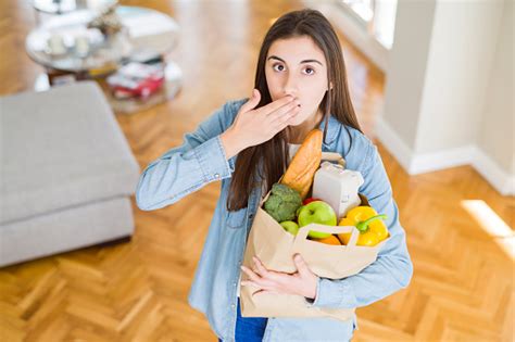 건강 한 식료품을 들고 아름 다운 젊은 여자는 실수로 두려움의 표현 침묵에 무서 워 비밀 개념에 대 한 수치와 충격을 손으로 입을 커버 가득 찬에 대한 스톡 사진 및 기타