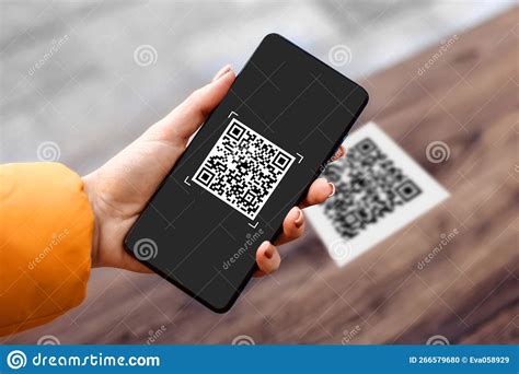 Female Hand Holding Black Mobile Phone With Qr Code On The Screen Stock